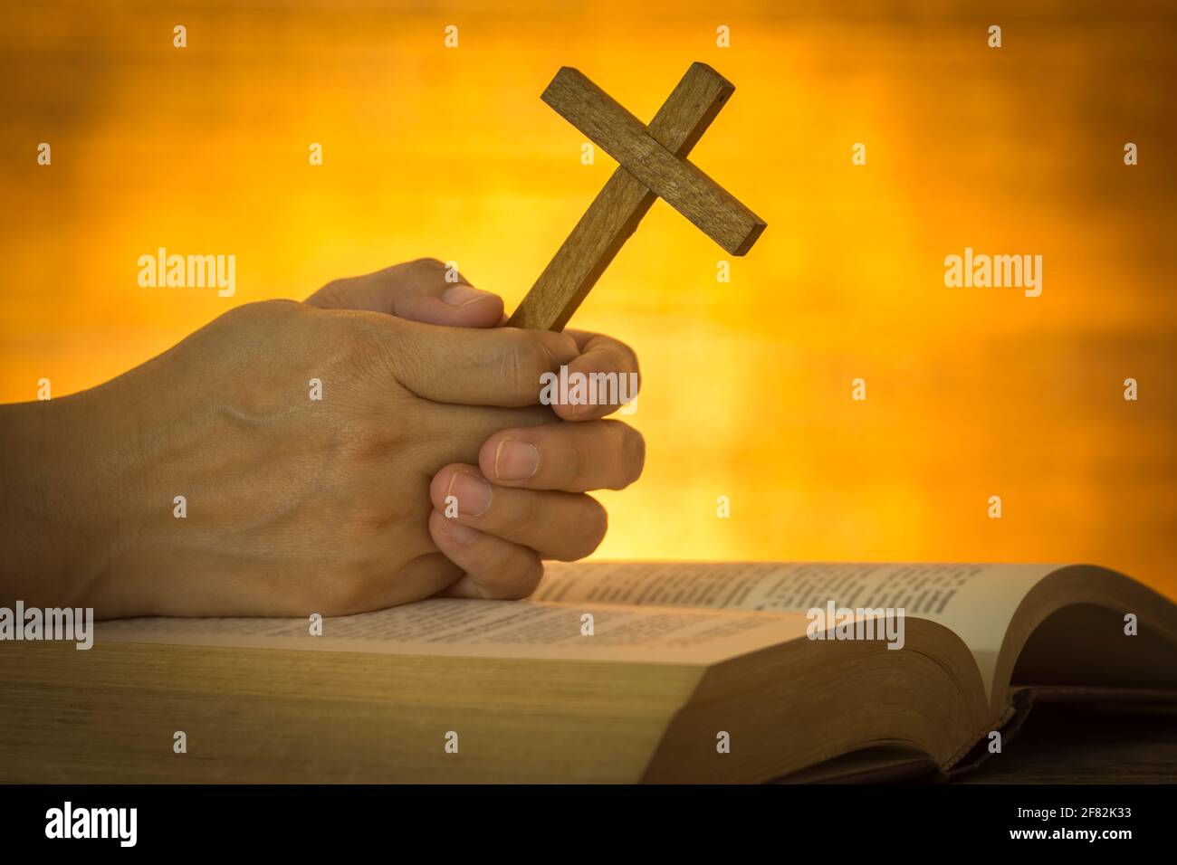 Human hands holding a cross on the Bible, pray to God Stock Photo - Alamy