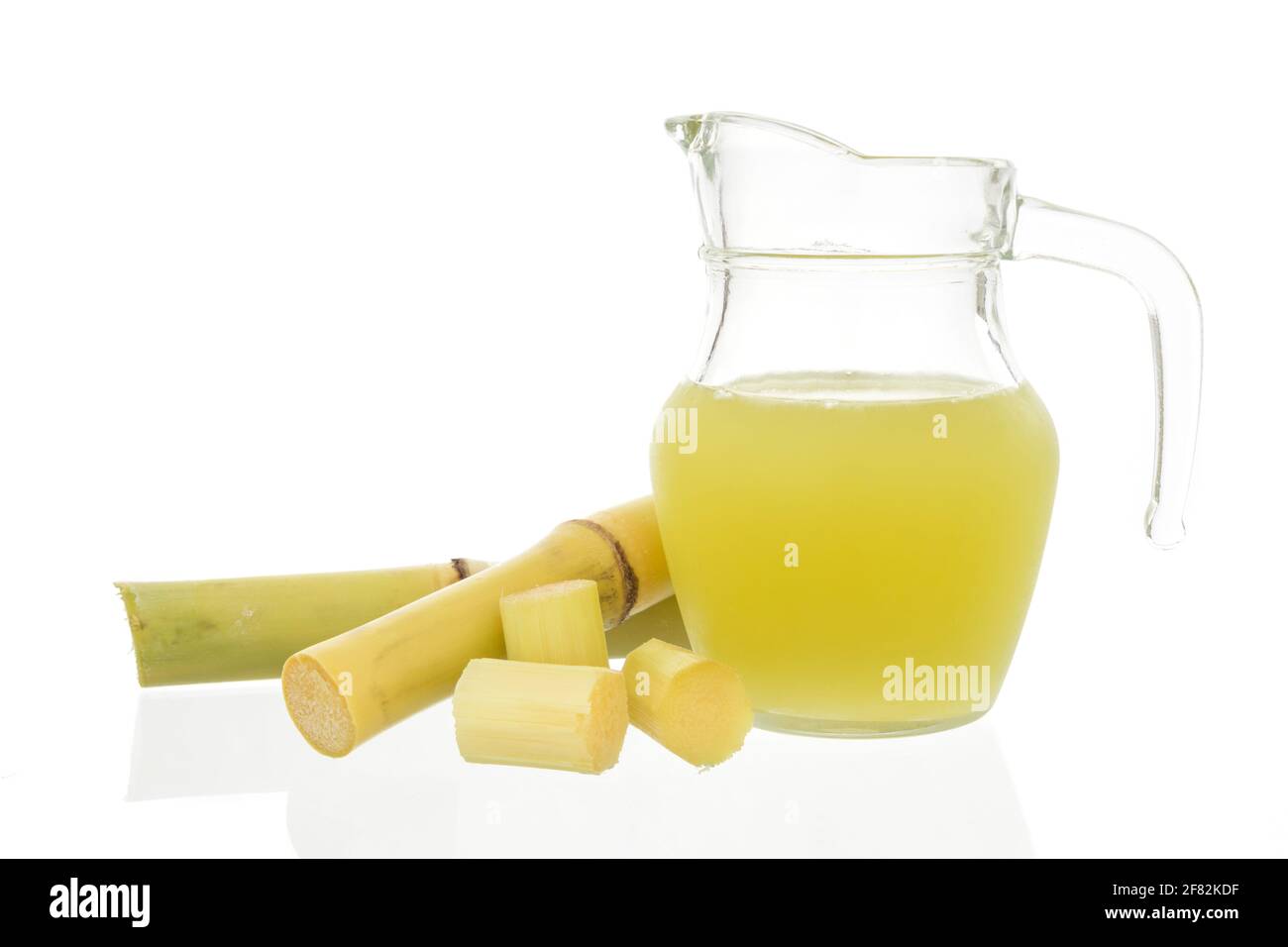 Fresh squeezed sugar cane juice in jug with cut pieces cane isolated on ...