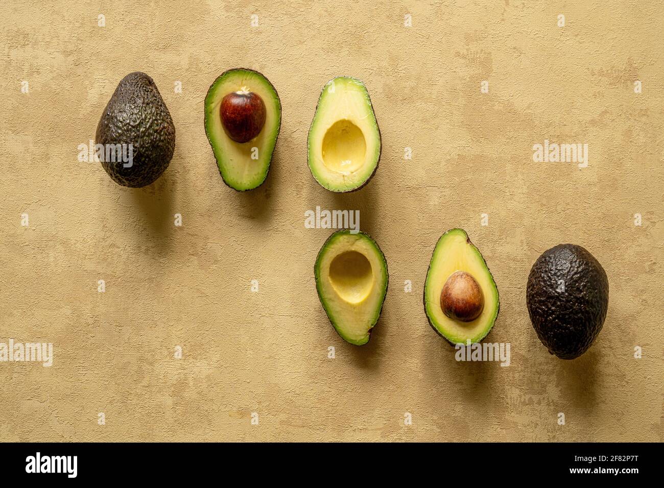 A creative top view of sliced and whole avocados put in symmetrical ...
