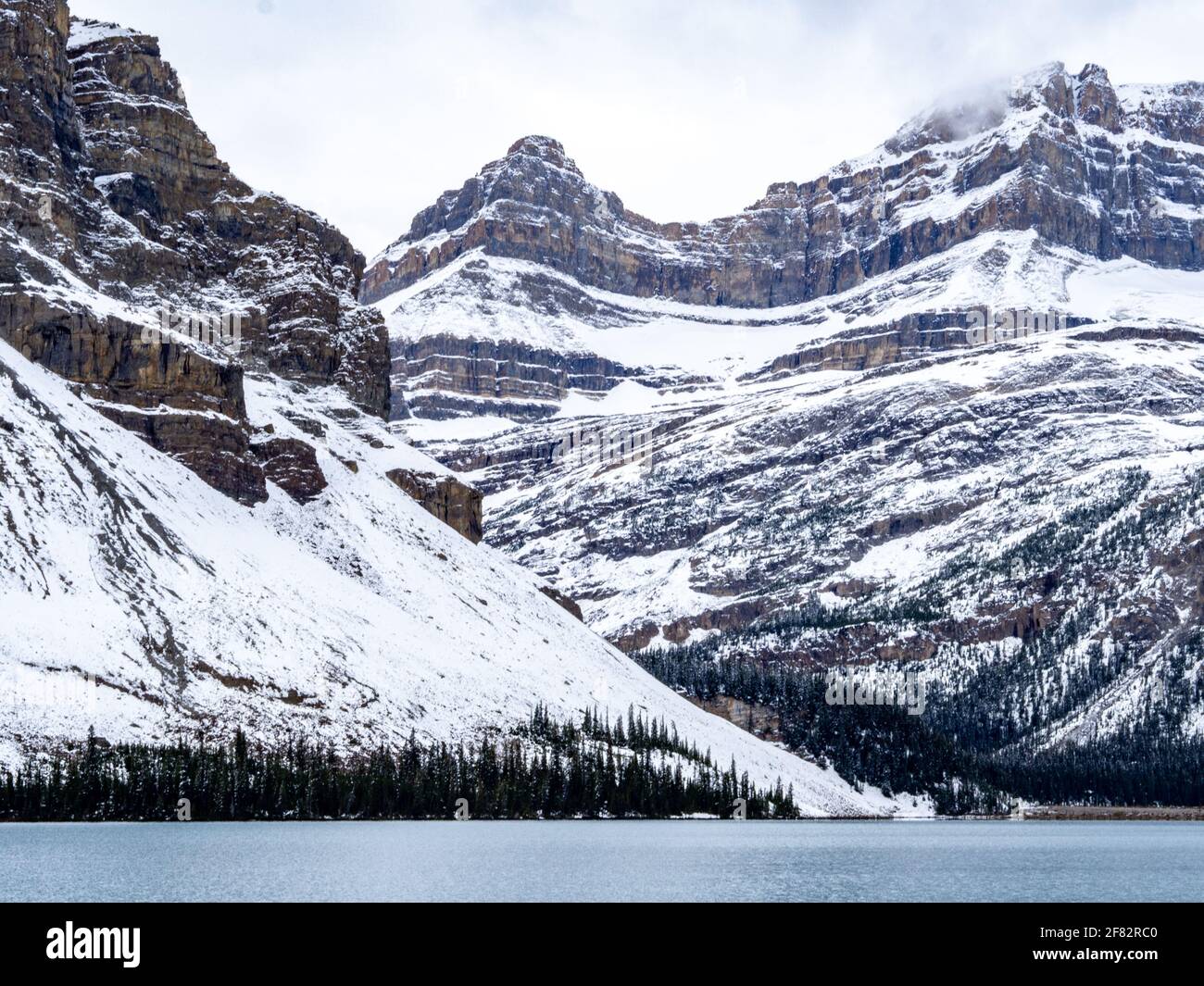 Tall mountains with snow behind a lake in winter with clouds Stock ...