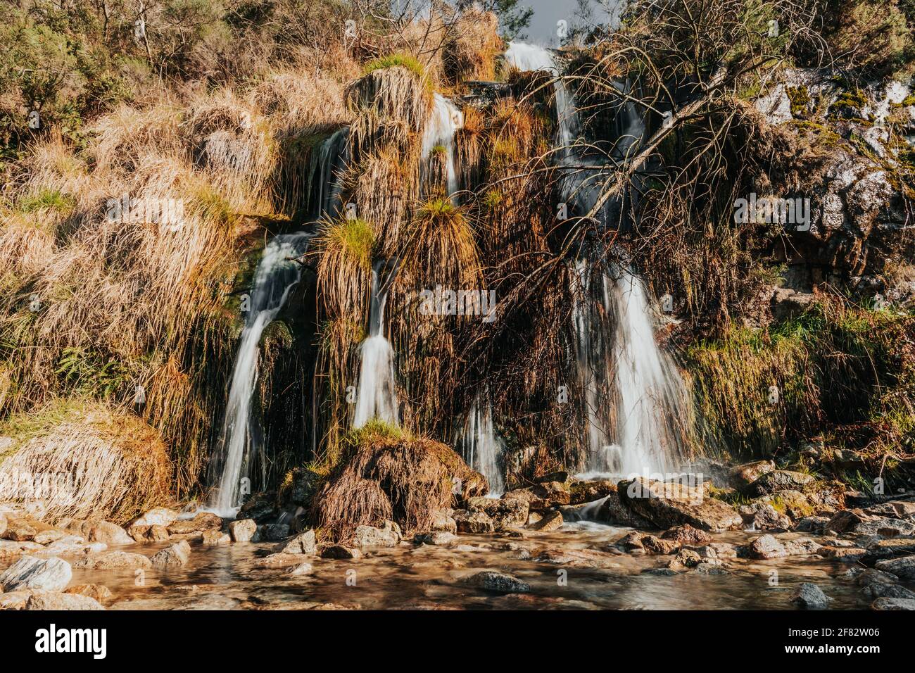 A low angle shot of a waterfall flowing down a rocky hill joining a ...