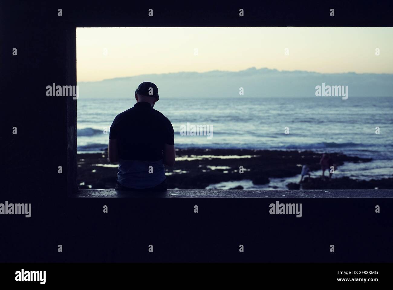 A silhouette of a person looking out of the balcony to the city view ...