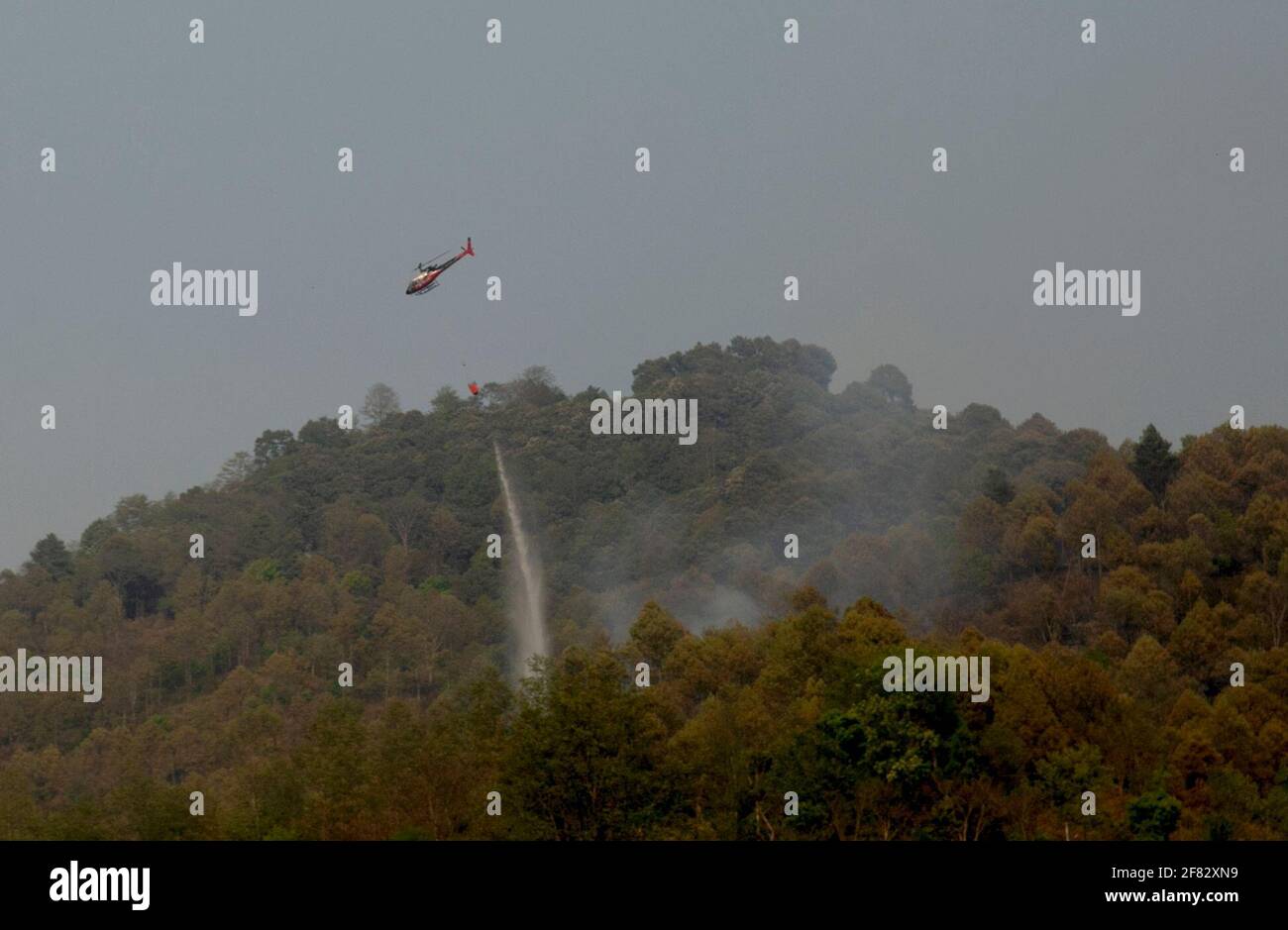 Kathmandu, Nepal. 11th Apr, 2021. A helicopter drops water on a forest ...