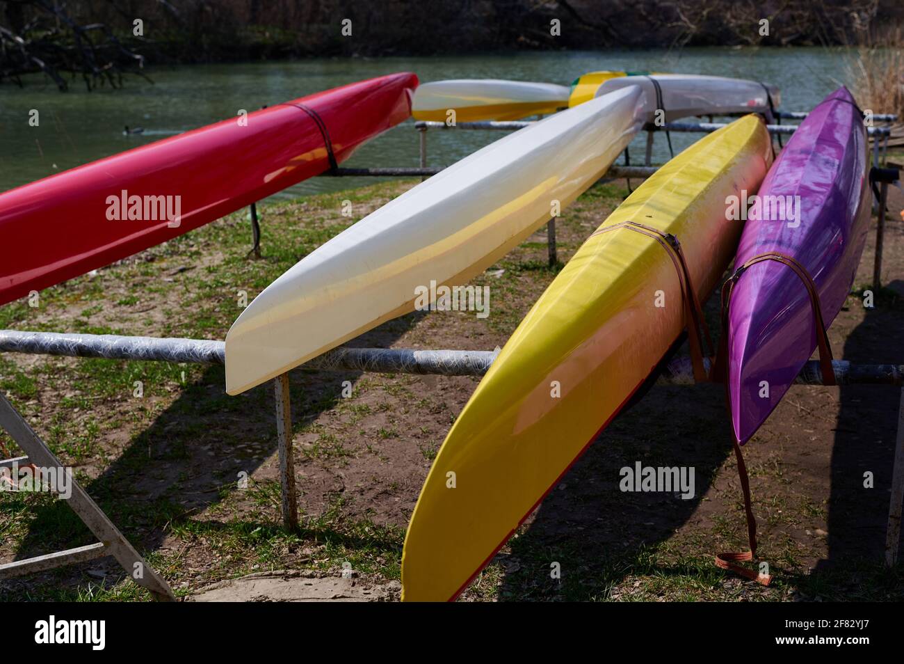colorful canoes lie on the river bank. close-up view from the top side ...