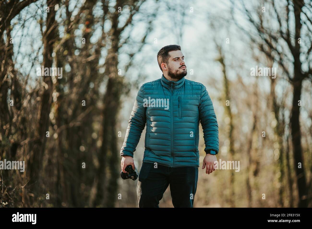 A handsome Caucasian male with camera in hand walking in a forest Stock ...