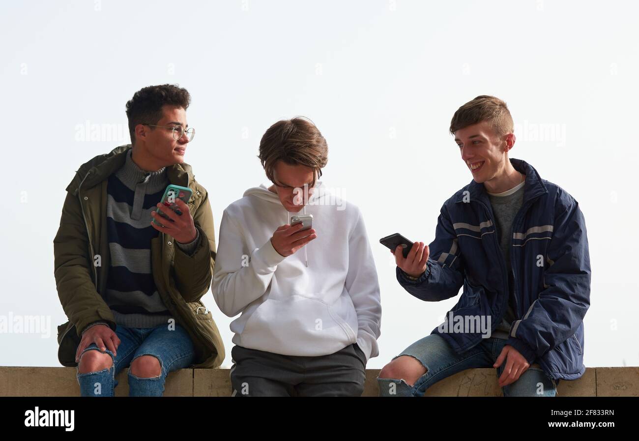 A closeup of three young Caucasian and Hispanic guys socializing and ...