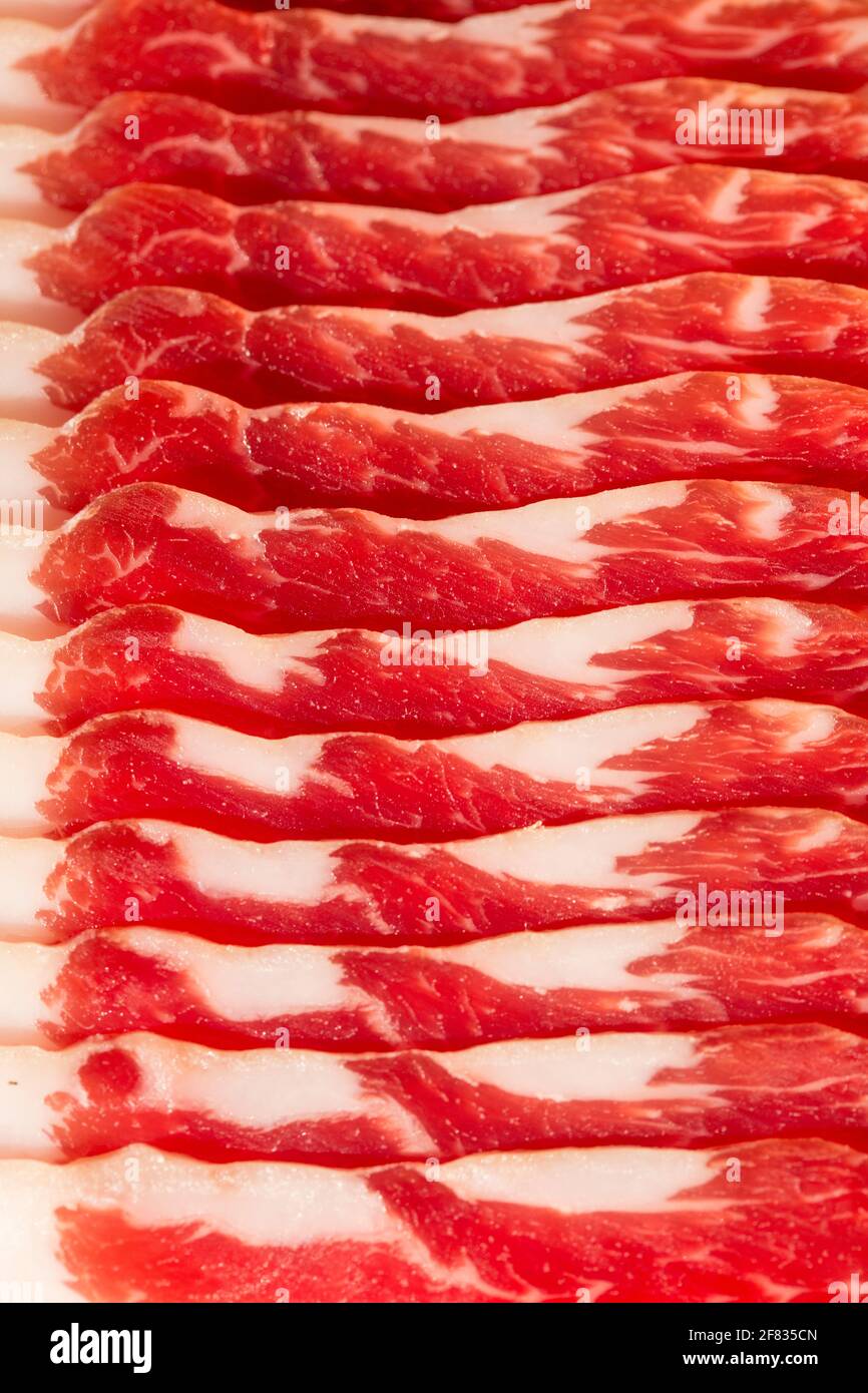 Thin slices of air dried raw Italian pancetta bought from a supermarket ...
