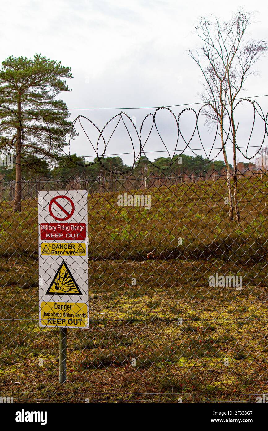 Danger, Keep Out warning sign behind a barbed wire fence protecting ...