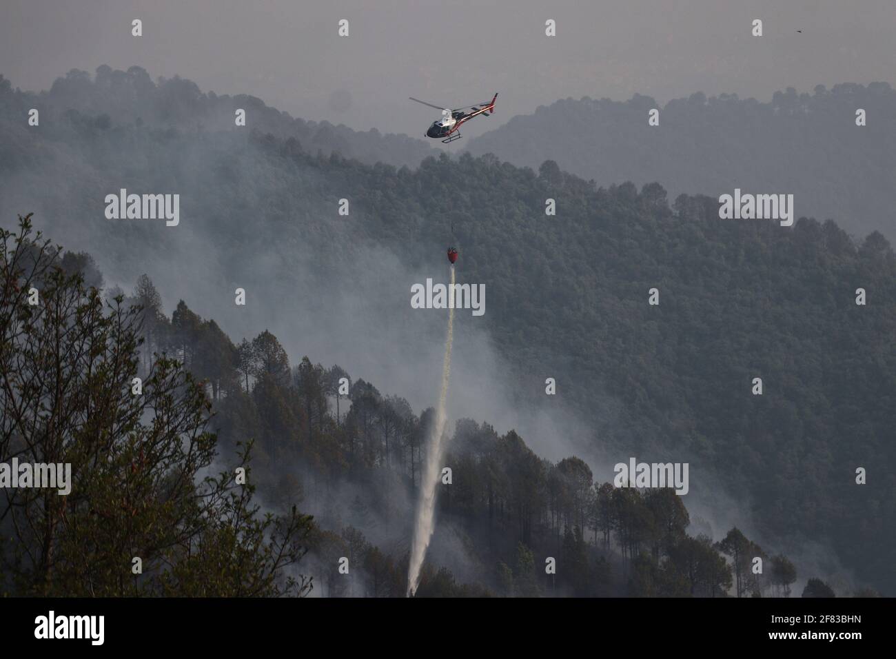 Kathmandu, NE, Nepal. 11th Apr, 2021. A helicopter pours water to douse ...