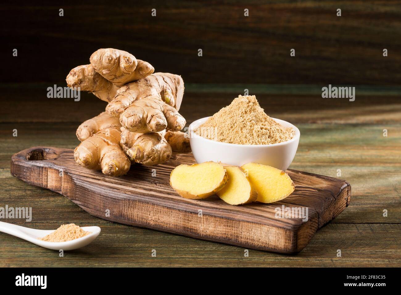 Fresh sliced ginger root and ground ginger on wooden background ...