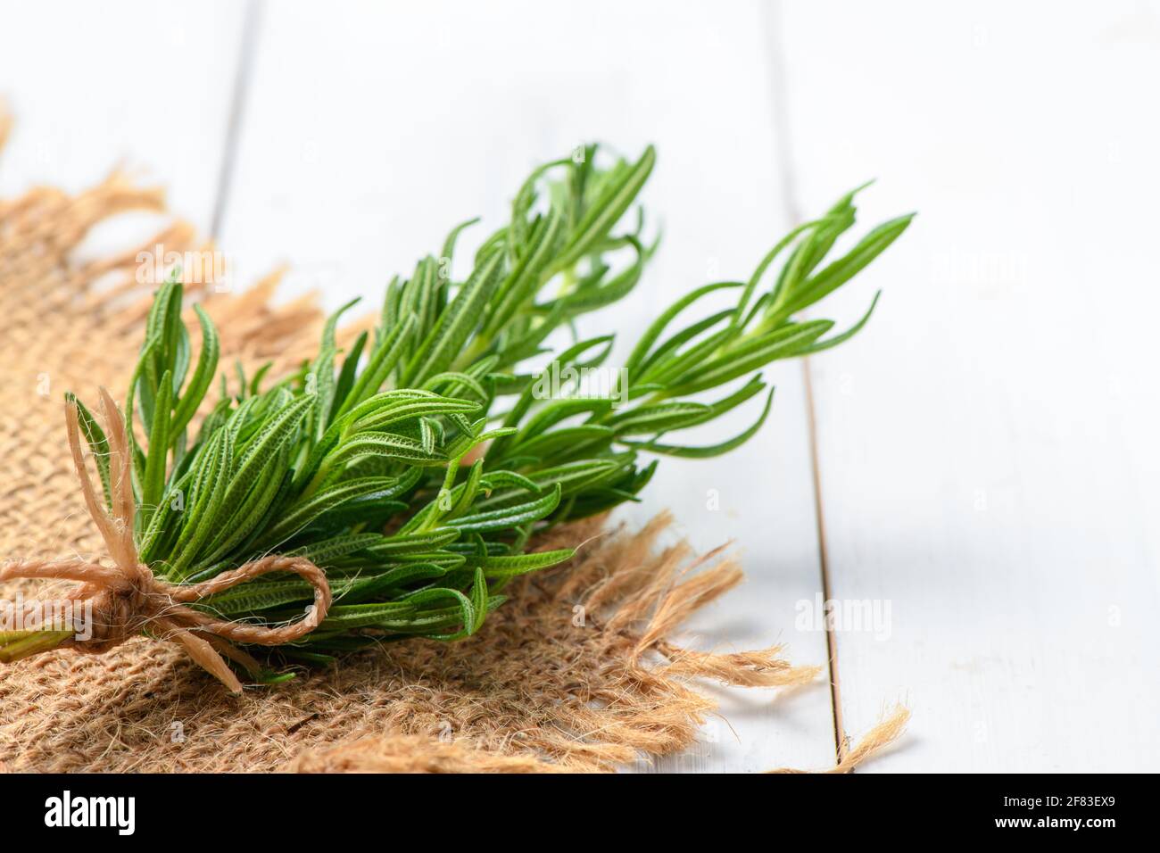Branch of fresh rosemary on sack and white wood background. Rosemary is ...