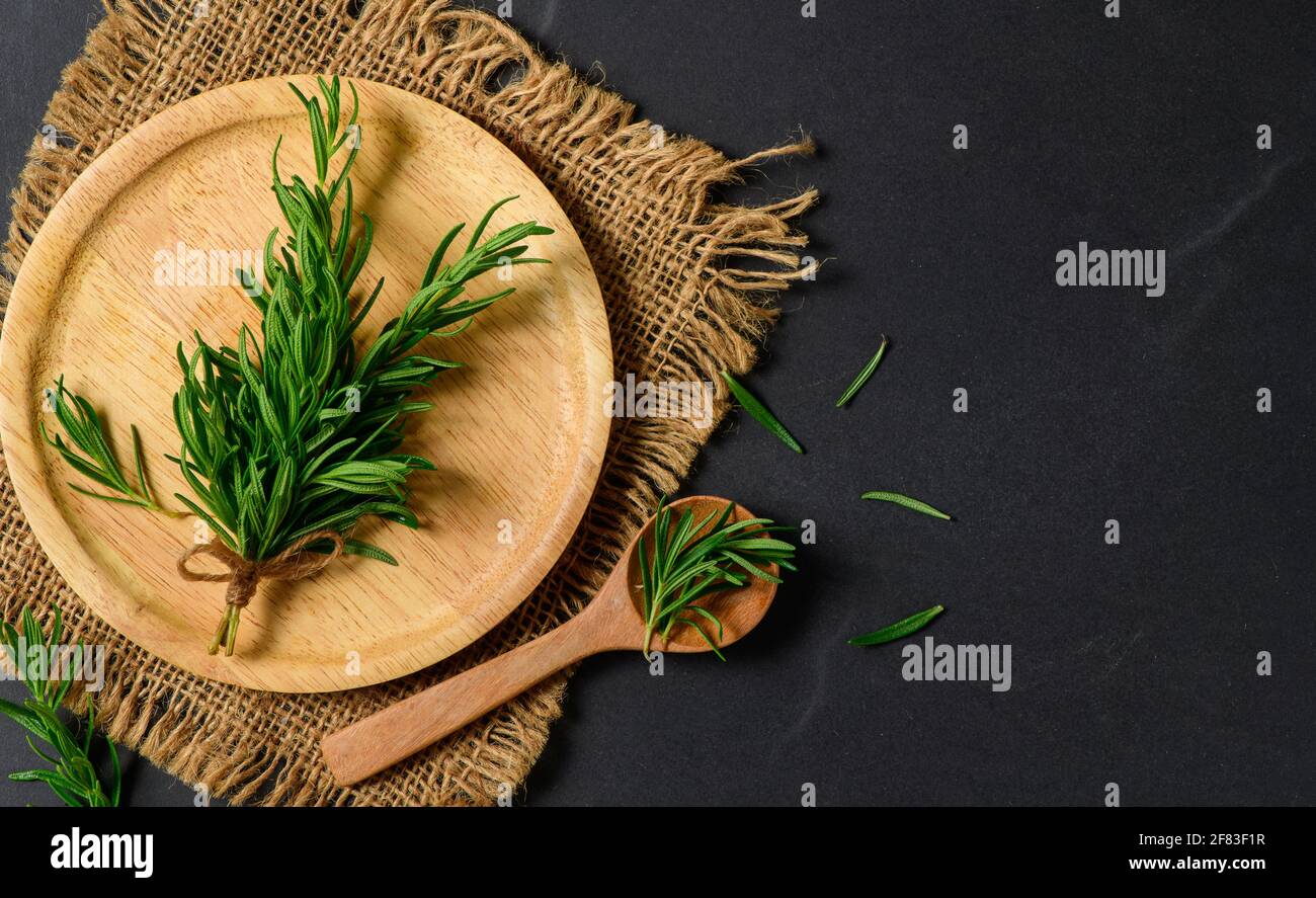 Top view of Branch fresh rosemary in wood plate on black background ...