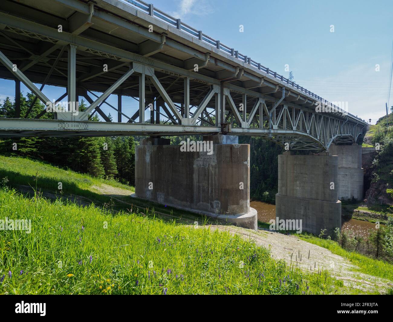 grey metal bridge over a river in summer with green grass Stock Photo ...