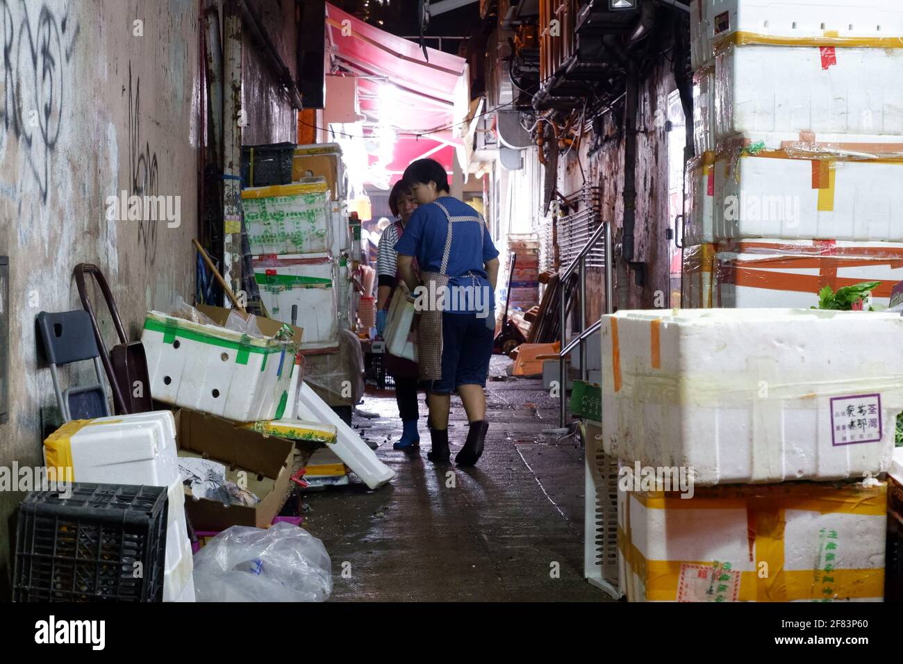 Hong Kong street scene with two workers carrying stuff in alleyway in ...