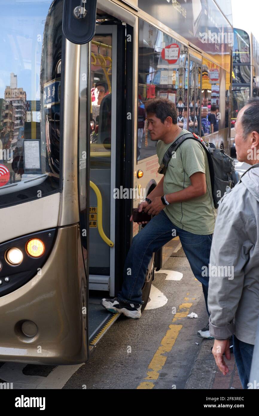 Hong Kong street scene with a man boarding KMB bus in Tsim Sha Tsui ...