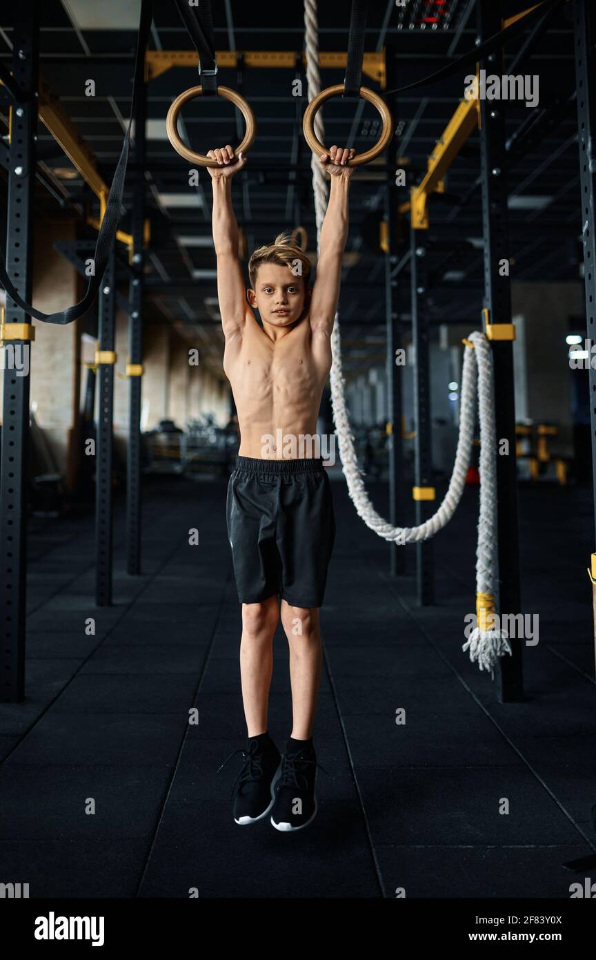 Athletic boy doing exercise on rings in gym Stock Photo - Alamy