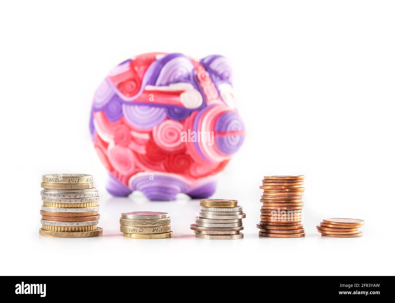 Multiple coins stacks in front of defocused and abstract piggy bank ...
