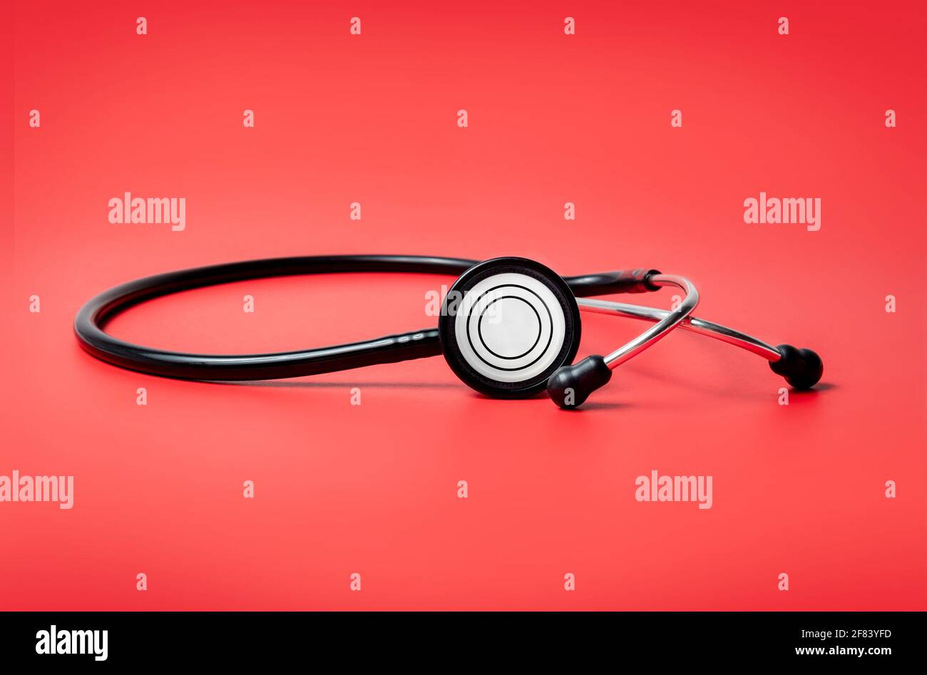 Black Stethoscope on red background. Healthcare background. Used by ...