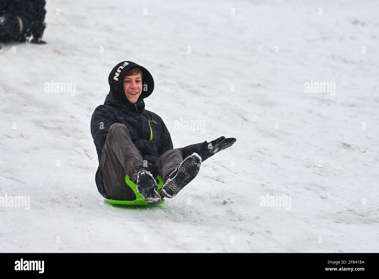 Moscow - 01.12.2021 - Teenage boy slides on sled, rolling down snowy ...