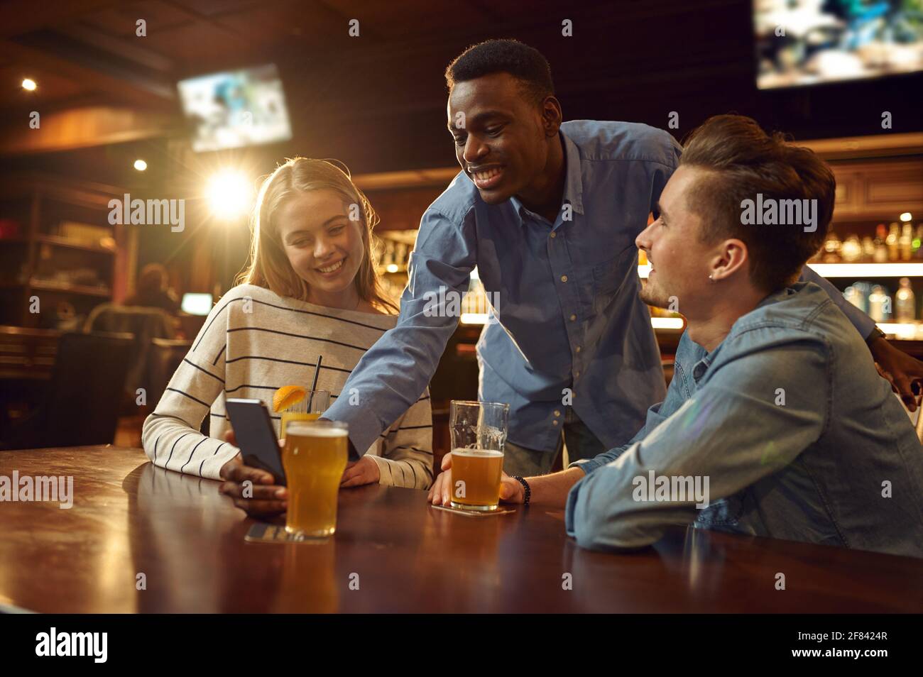 Friends look at photos on phone in bar Stock Photo - Alamy