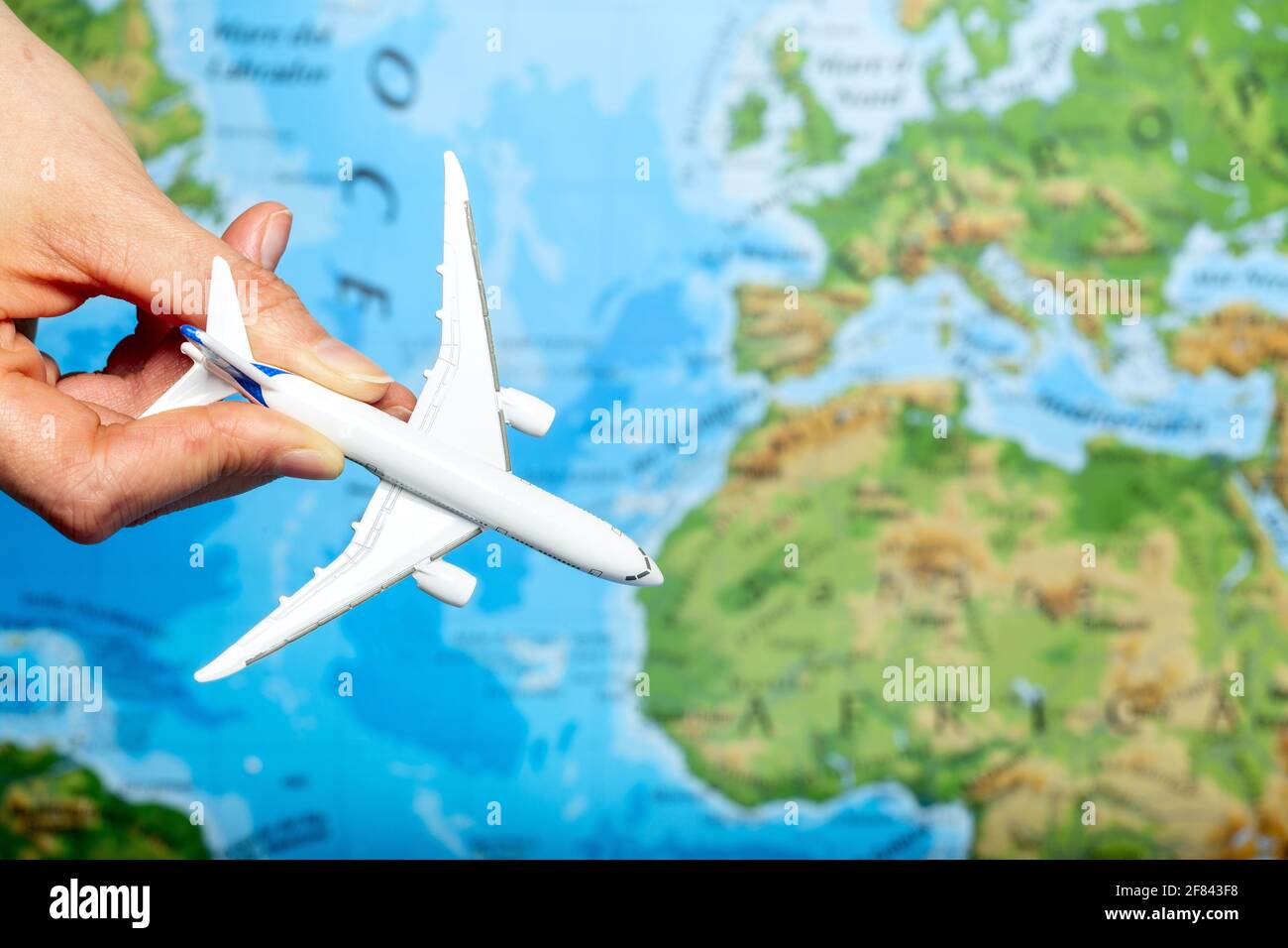 Passenger plane in a female hand on the background of the globe. Flight ...
