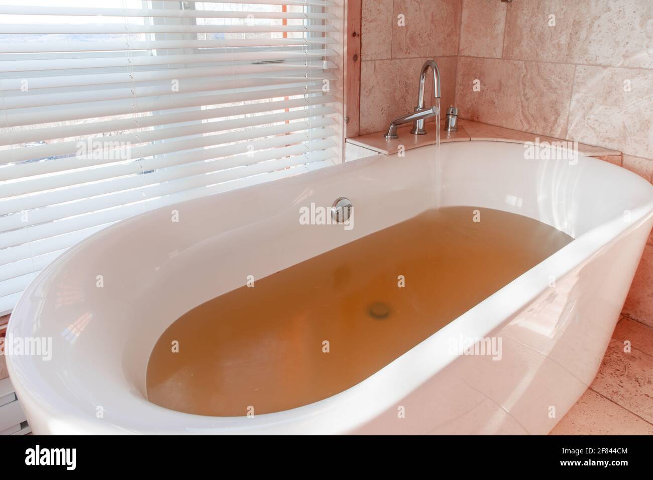 view of a bath filled with tinted color water next to a window with ...
