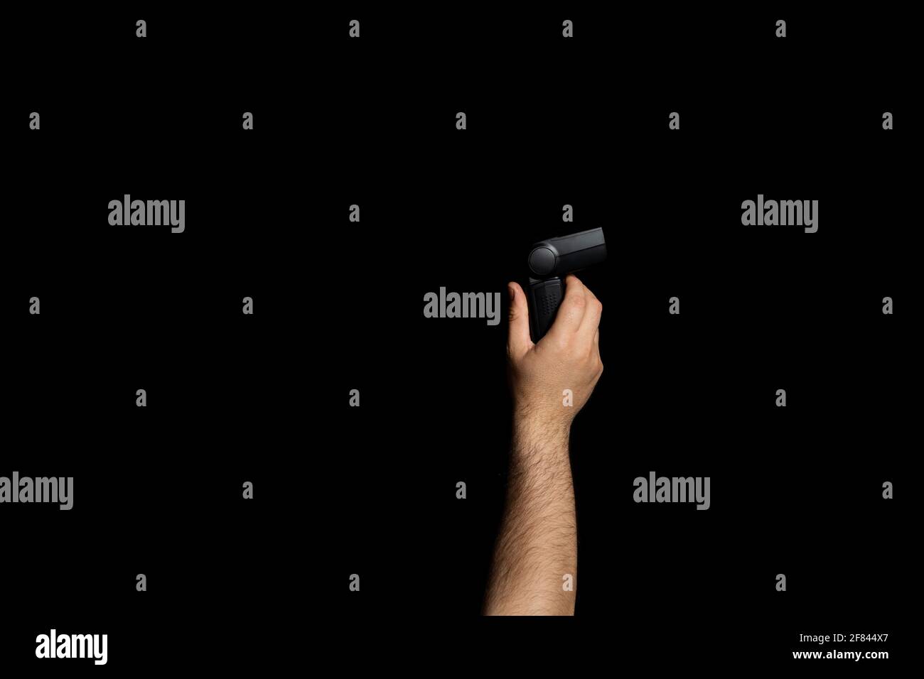 Raised man's hand holding a hand flash isolated on a black studio ...