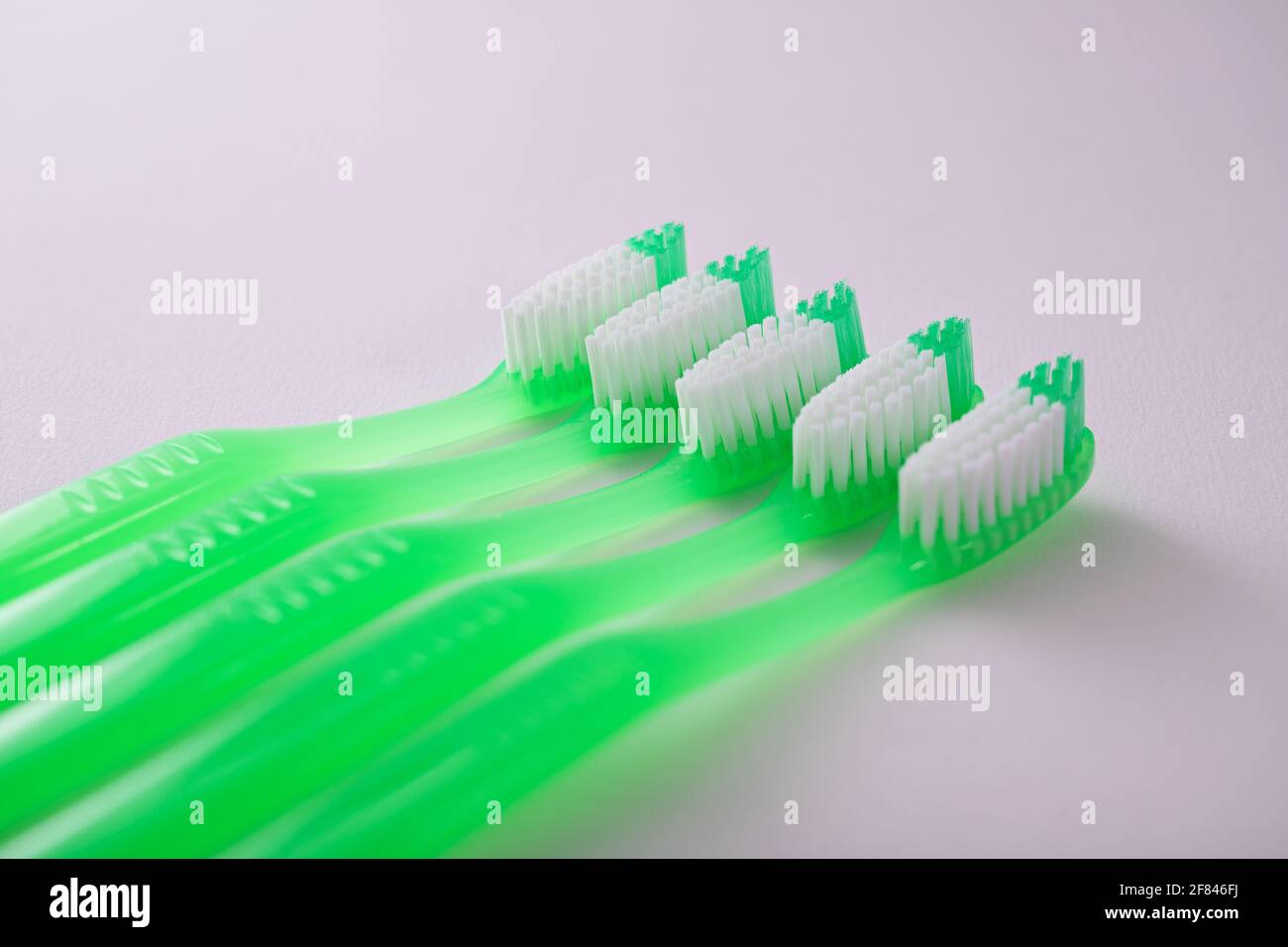 A shot of five green toothbrushes in a row isolated on white background ...