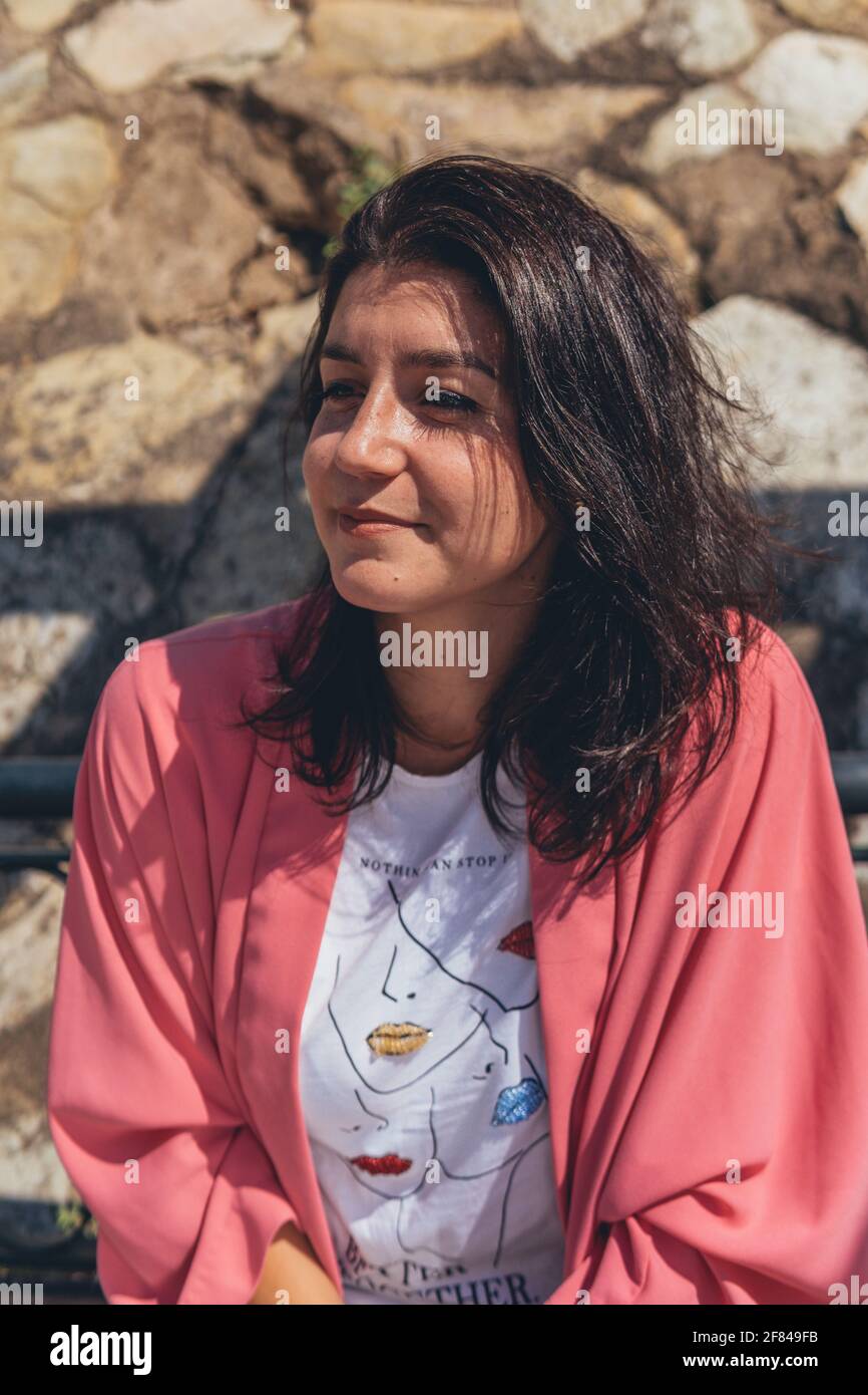 A young and cheerful Spanish female smiling with the sunlight on her ...