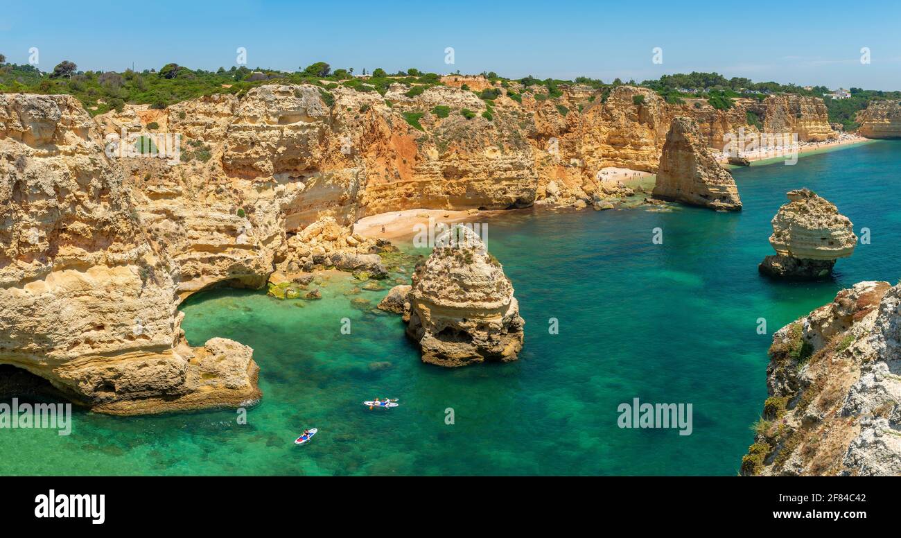 View of cliff of craggy sandstone rocks, rock formations and kayakers ...