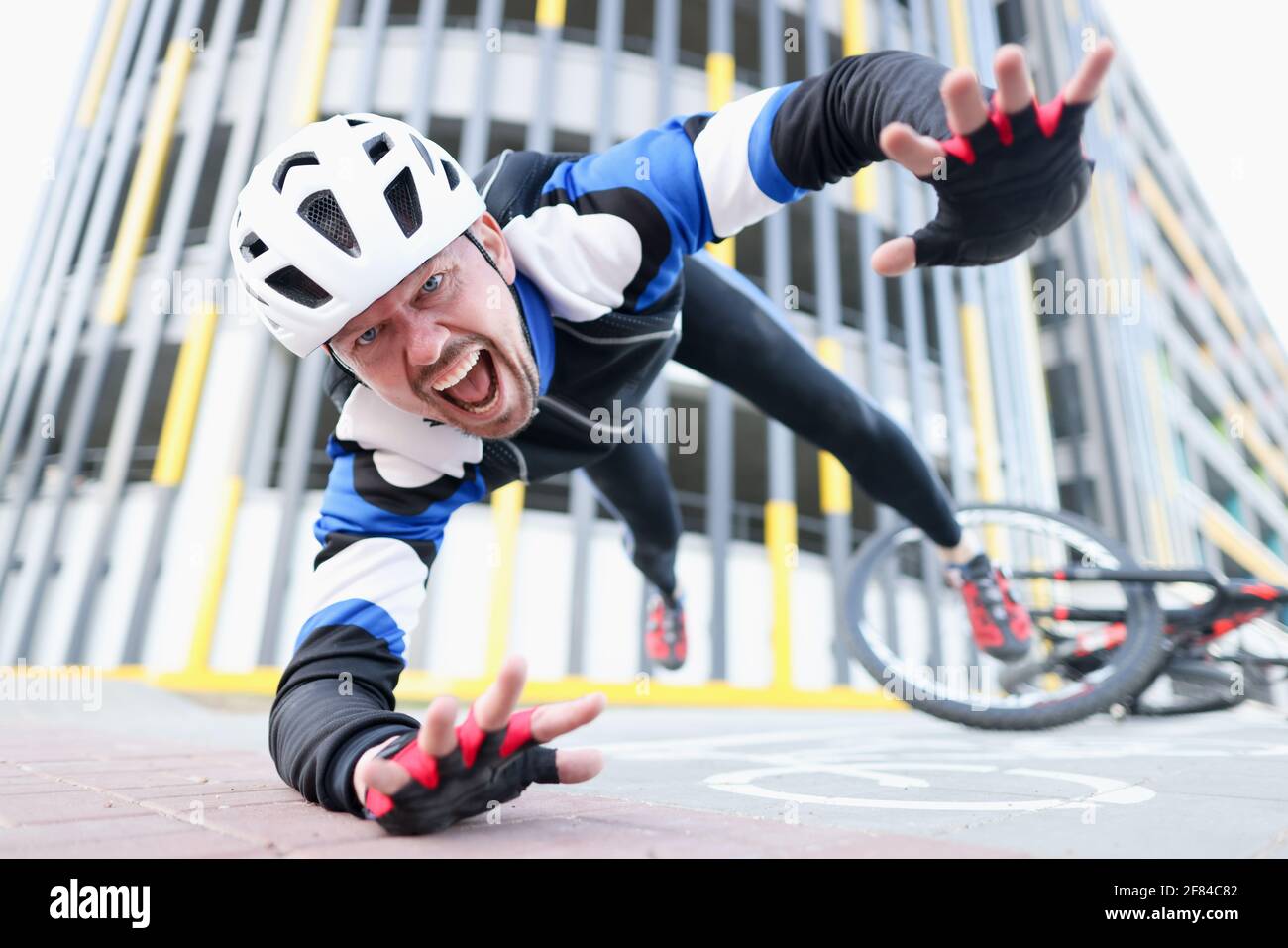 Young male cyclist wearing helmet and protective gear fell off bike and ...