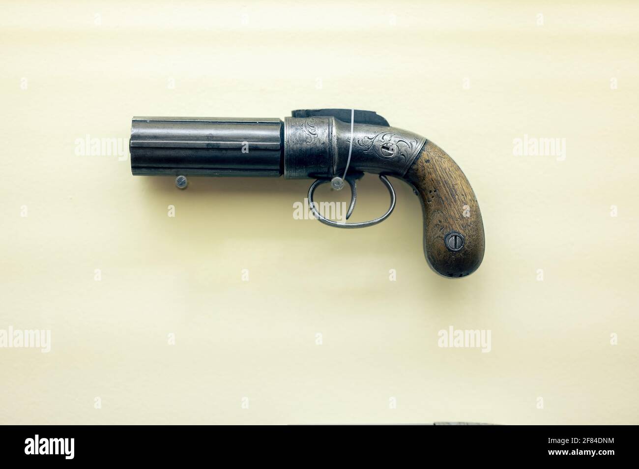 An old vintage pepper-box revolver isolated on a light yellow ...