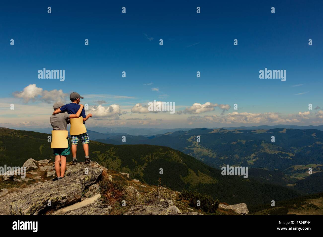 Two small children, brothers boys standing on one rocky peak, a ...