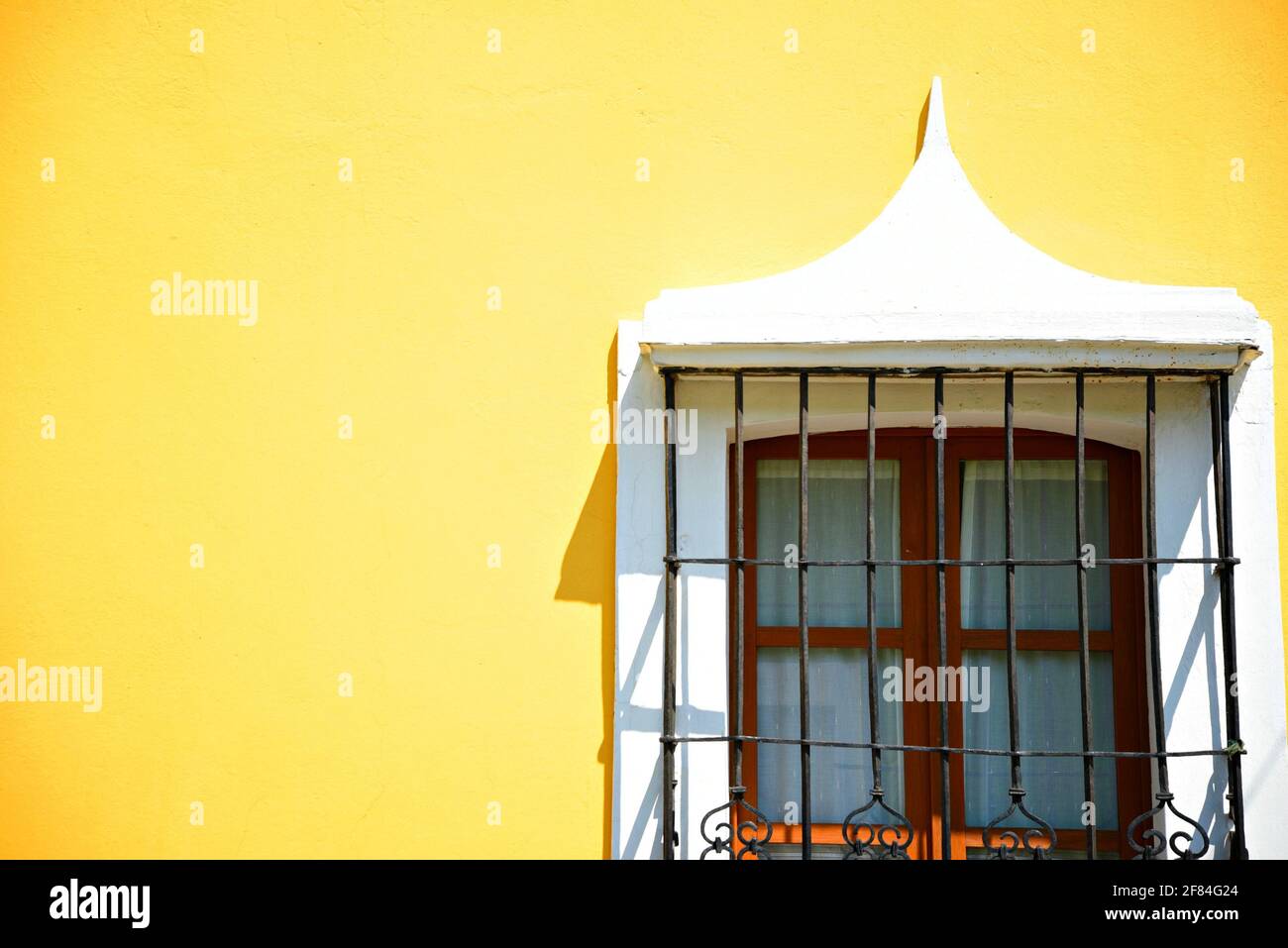 Colonial house window with handcrafted iron grilles and white trim on a ...