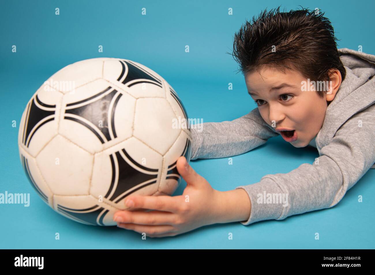 Closeup of a teenage boy, goalkeeper, catching a soccer ball, lying on ...