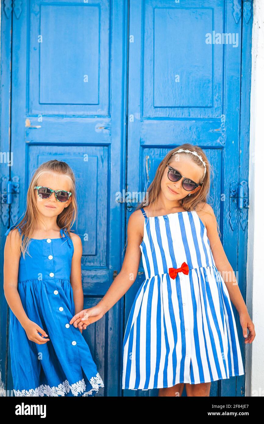 Little happy girls in dresses at street of typical greek traditional ...