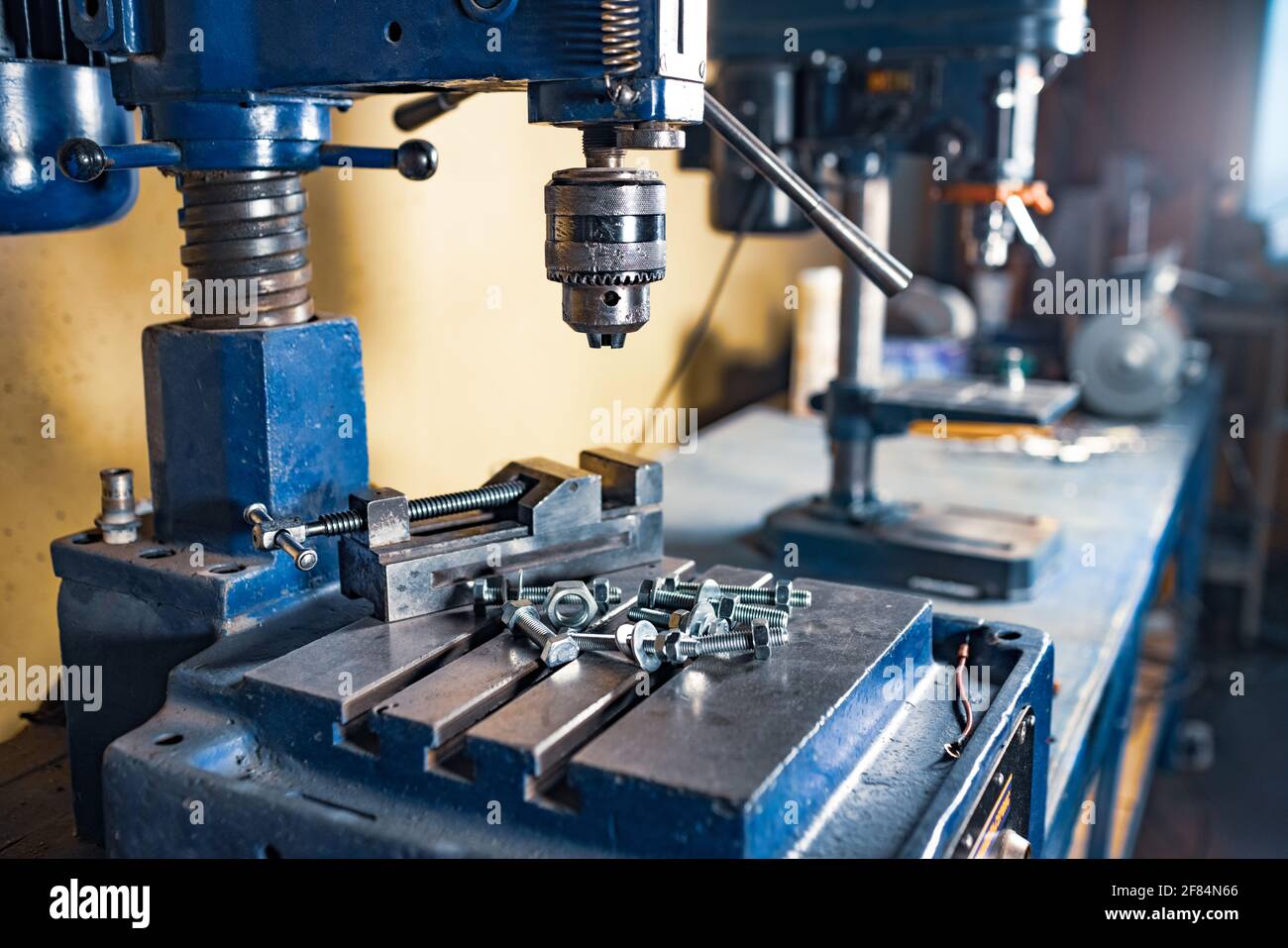 Metal chrome bolts and nuts lie on the drilling machine at the ...