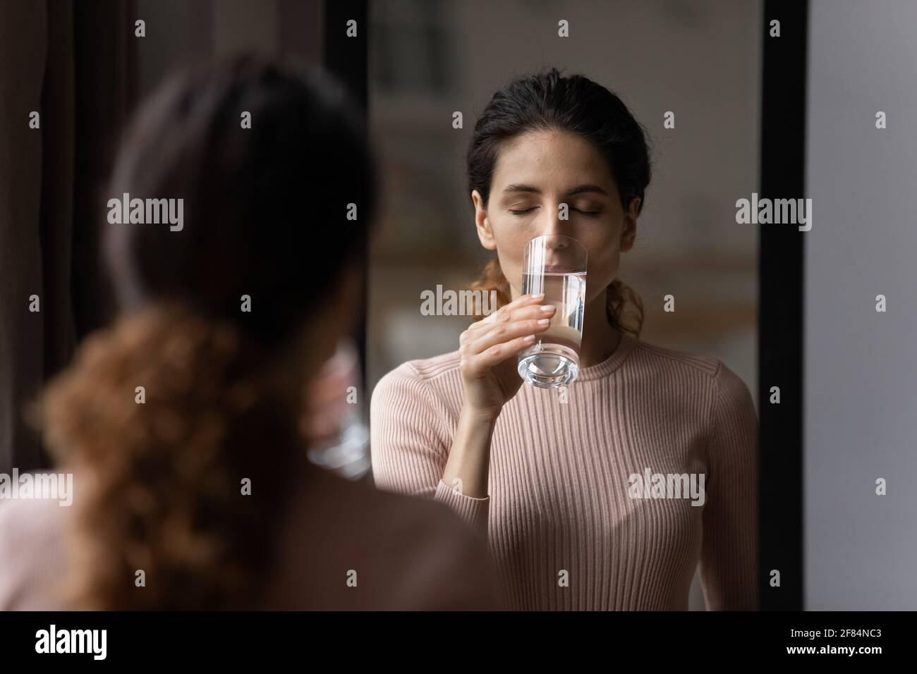Mirror reflection of young hispanic lady hydrating drinking water Stock ...