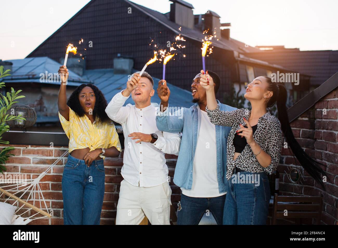Group of four cheerful friends in stylish outfits celebrating party on ...