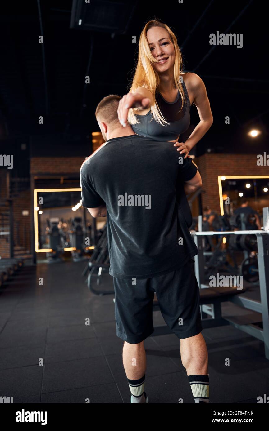 Strong man lifting a young lady at sports club Stock Photo - Alamy