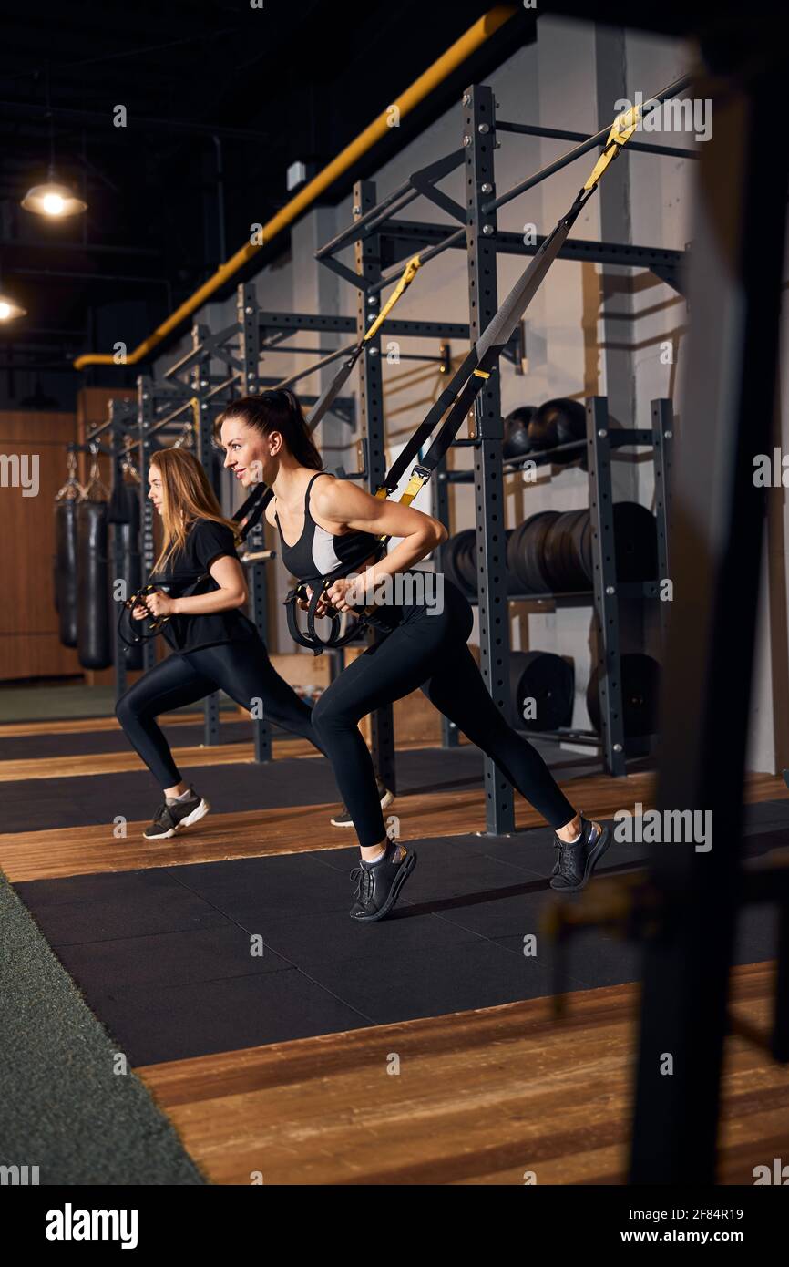 Athletic women exercising on pulling resistance gym machines Stock ...