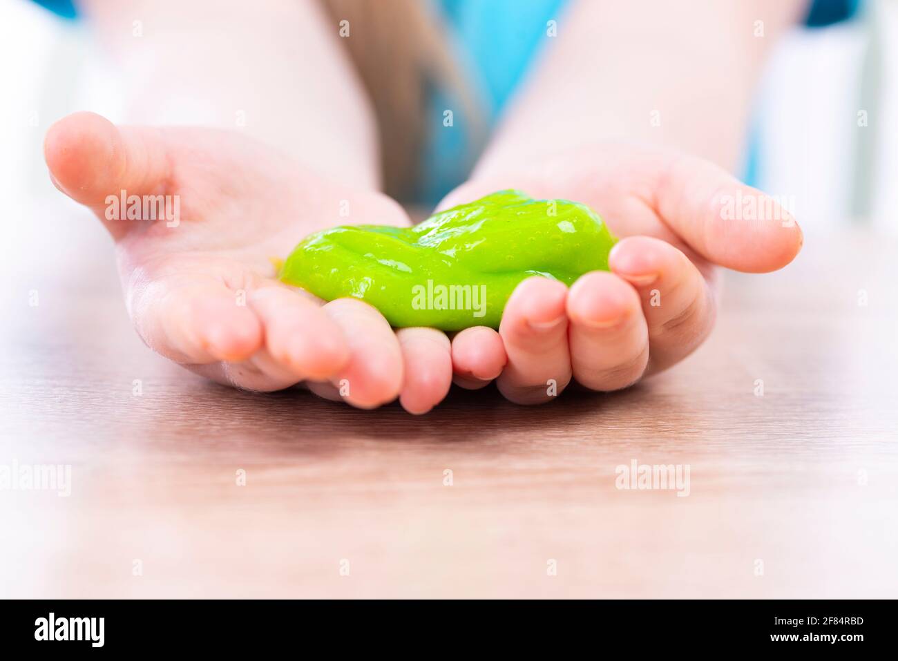 Yellow slime in the hands of a child. A small child is eating a slime ...