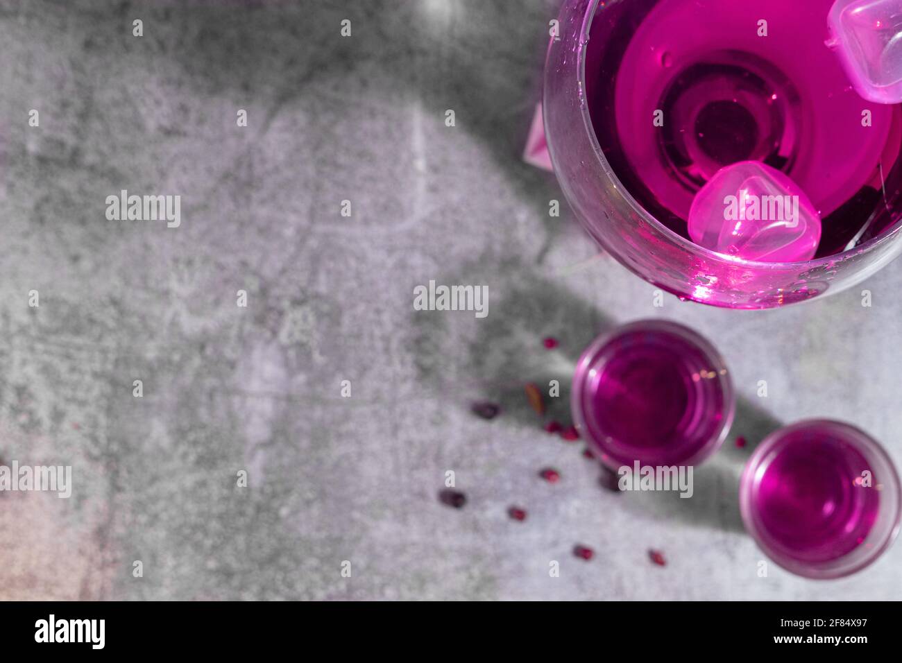 pink alcoholic drink top view with glass goblet and two shot glasses ...