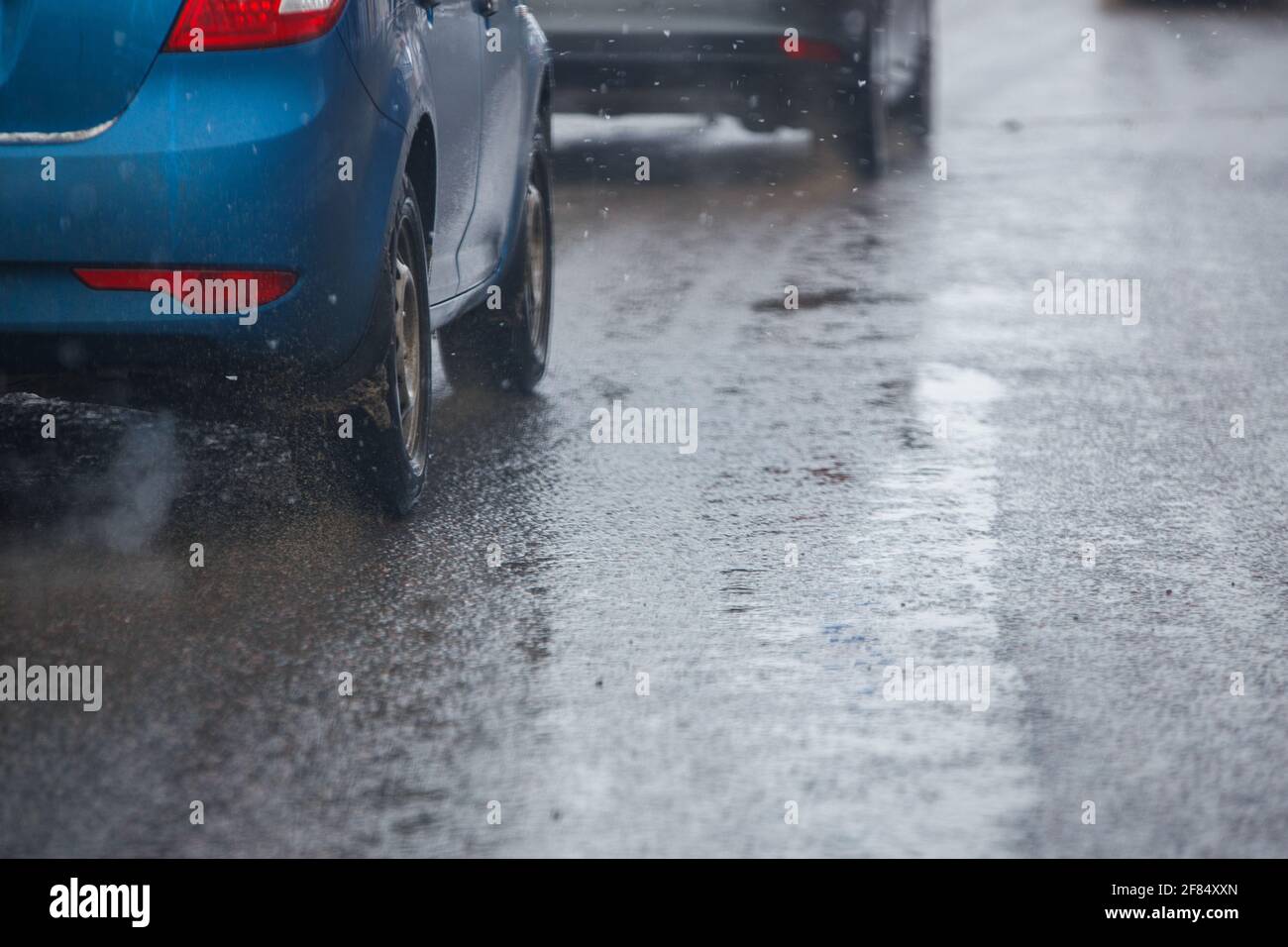 Dirt water splash flow from wheels of blue car moving fast in daylight ...