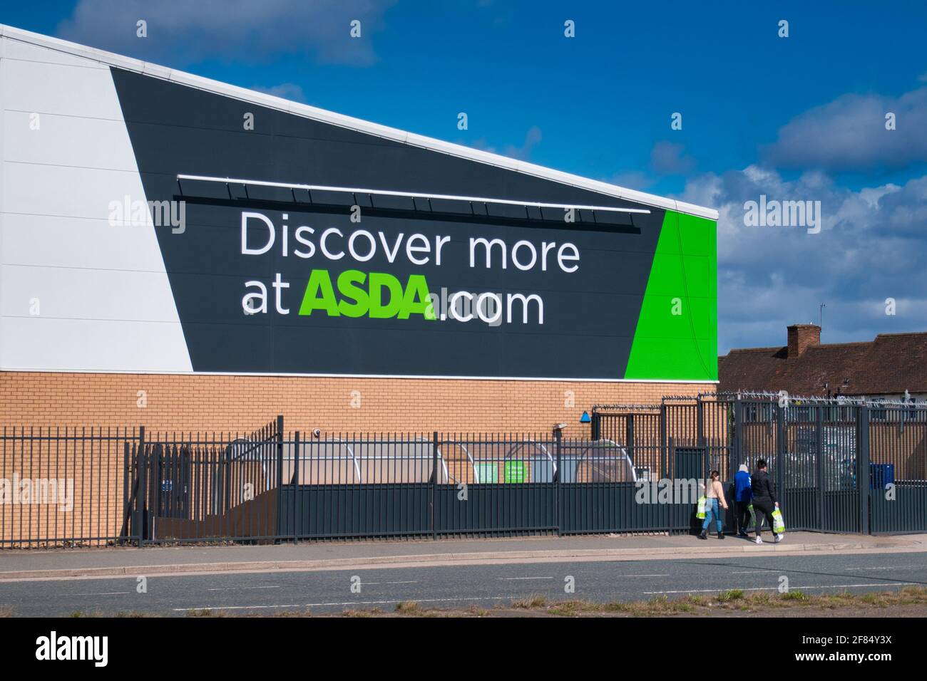 Store customers pass corporate signage at a store of the ASDA British ...