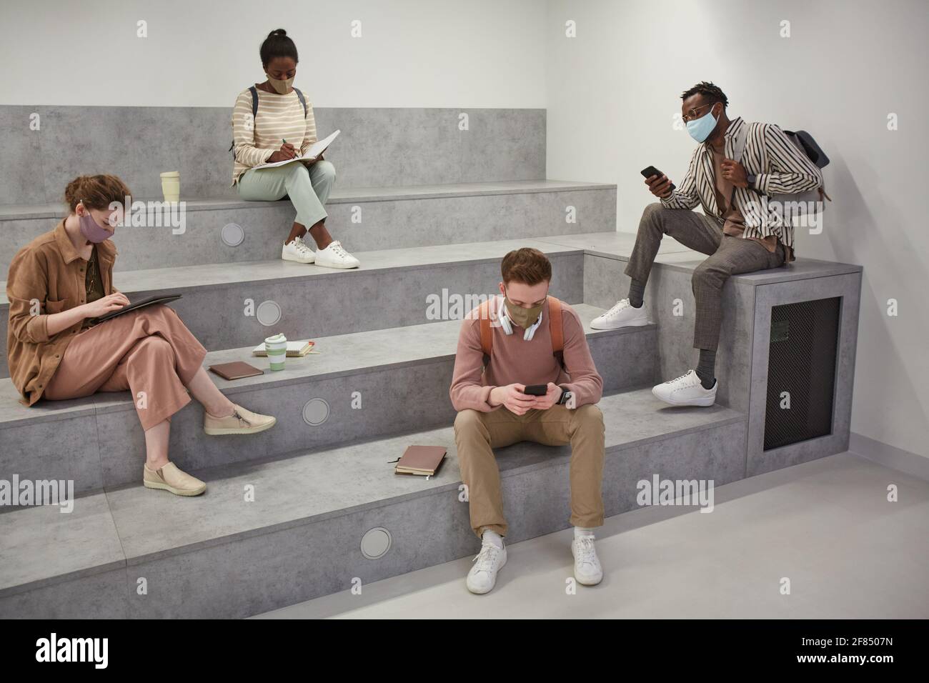 Wide angle view at diverse group of students wearing masks while ...