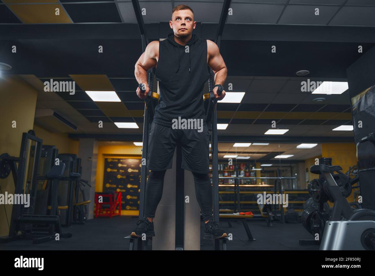 Strong muscular man doing push-ups on uneven bars in gym. Workout ...