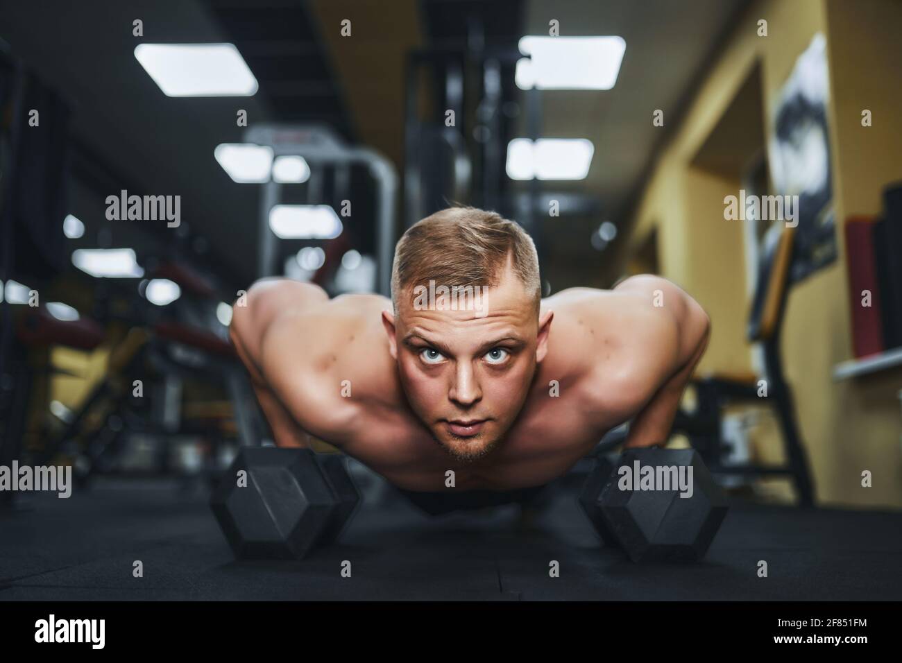 Young athletic man doing push-ups in gym. Muscular and strong guy ...