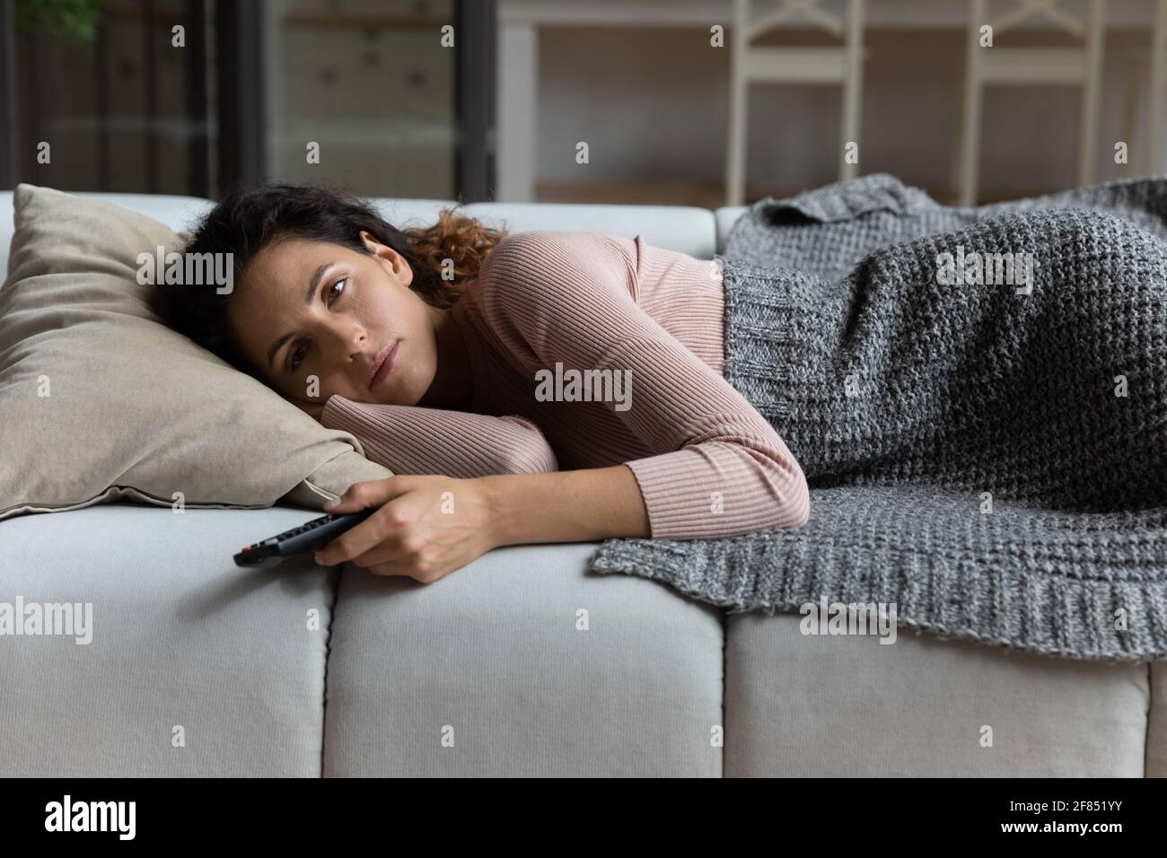 Tired young latin woman watch tv before fall asleep Stock Photo - Alamy