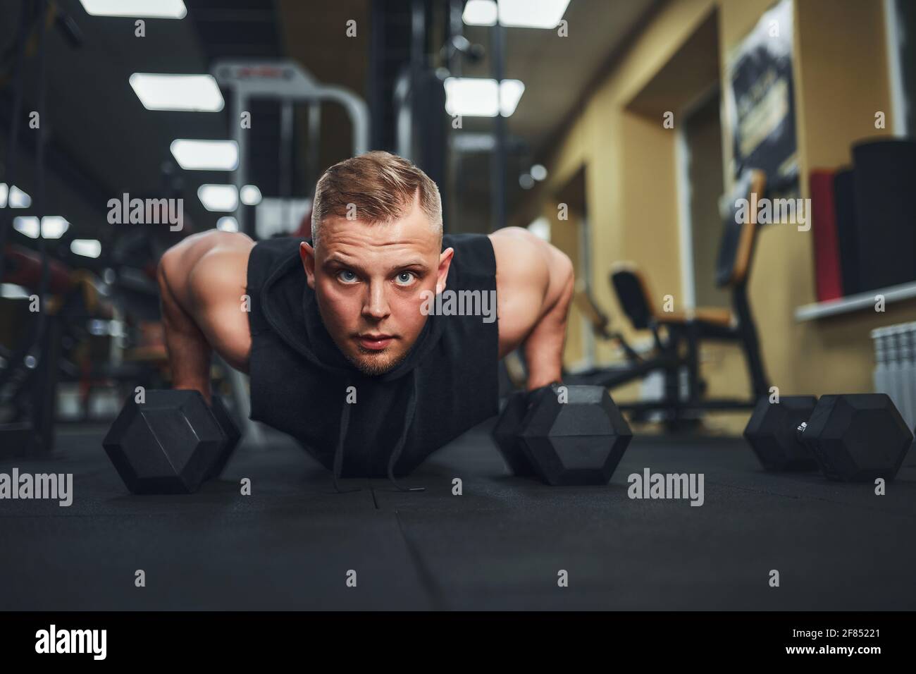 Young athletic man doing push-ups in gym. Muscular and strong guy ...